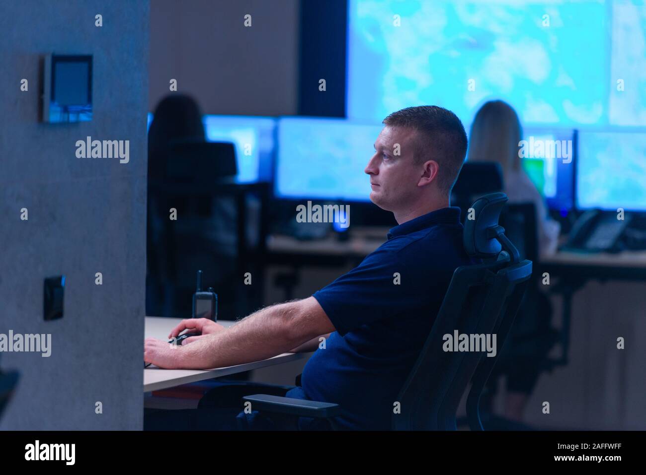 Side view of security system operator using walkie-talkie while looking ...