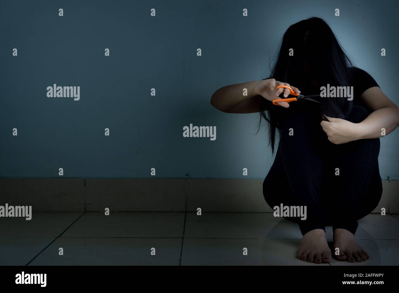 sad woman cry sitting alone and cutting her hair with scissors in a ...