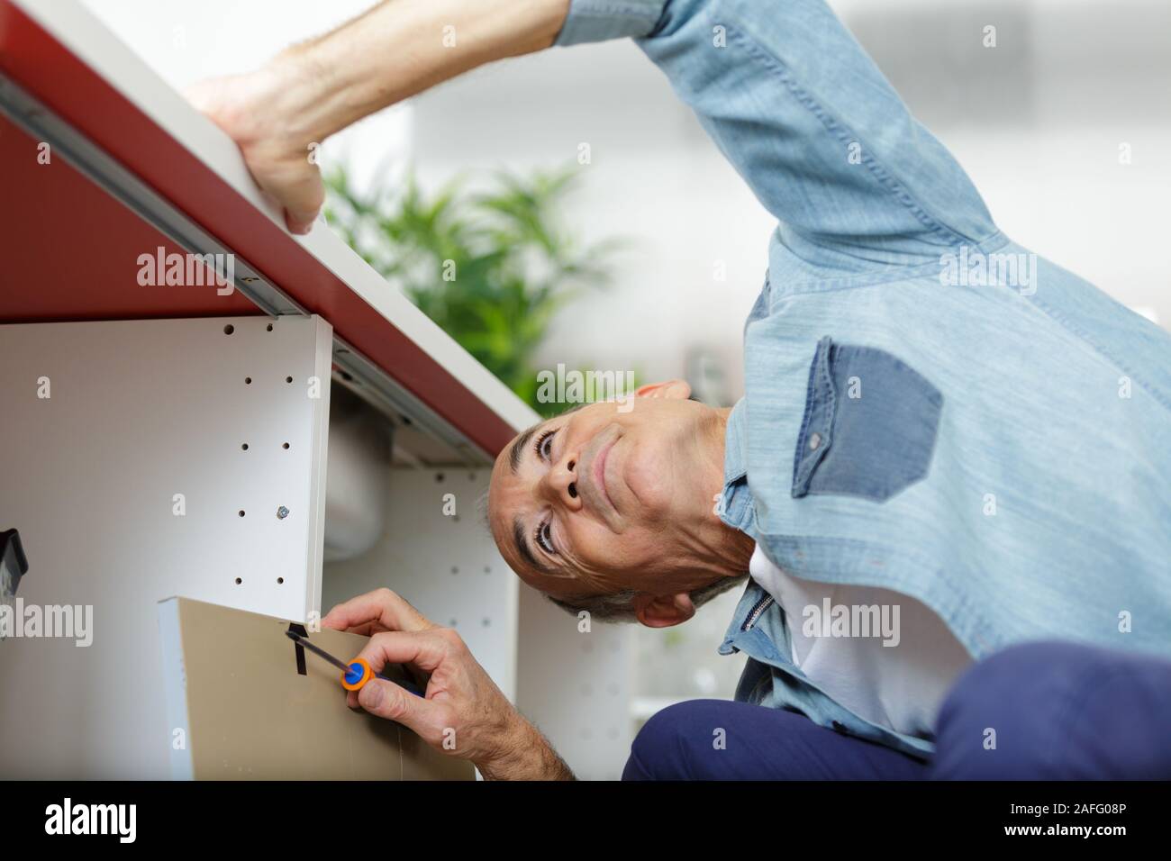 senior man assembling kitchen cupboard Stock Photo - Alamy