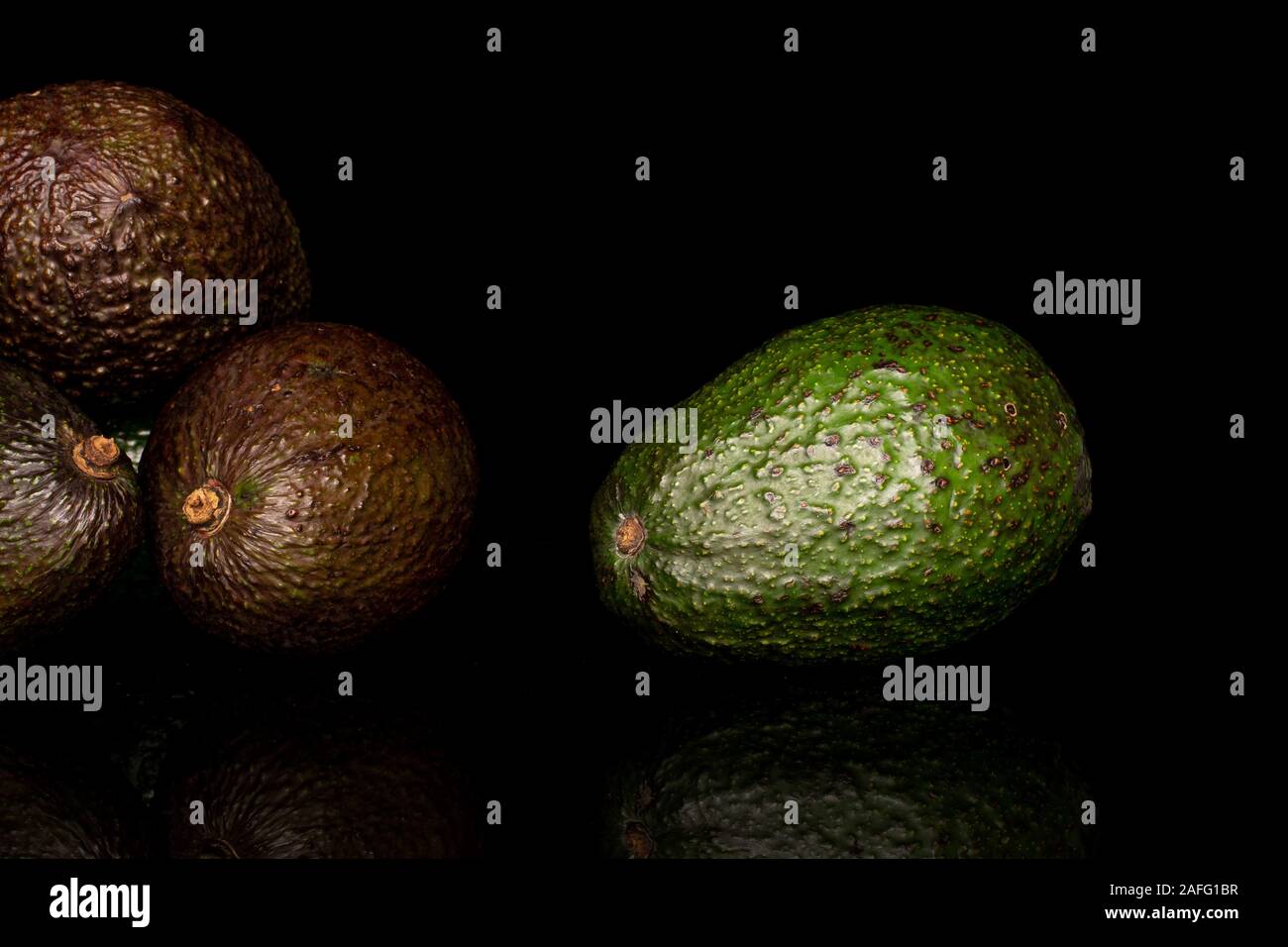 Group of four whole fresh green avocado isolated on black glass Stock ...