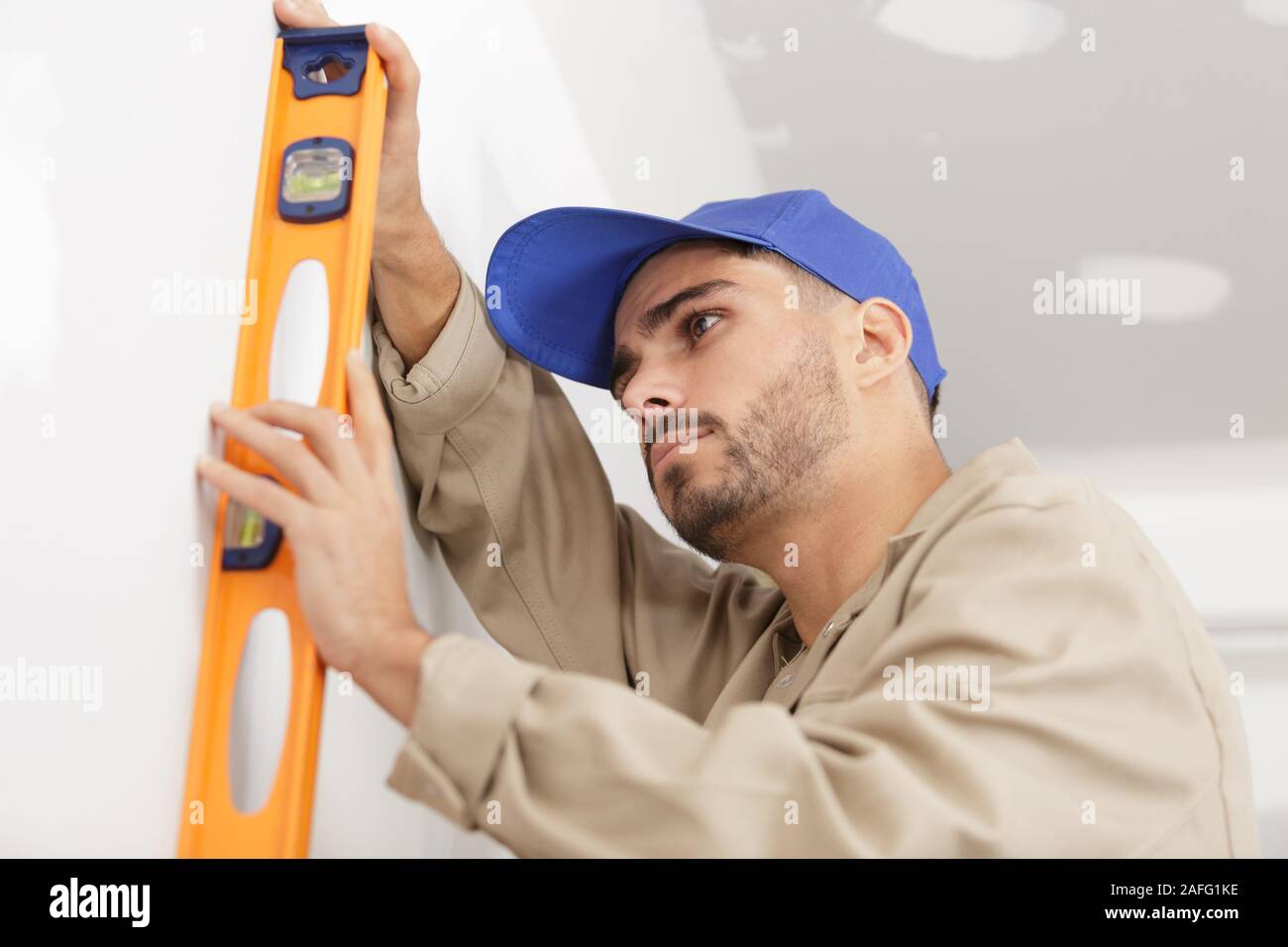 professional worker in helmet is measuring wall with level Stock Photo ...