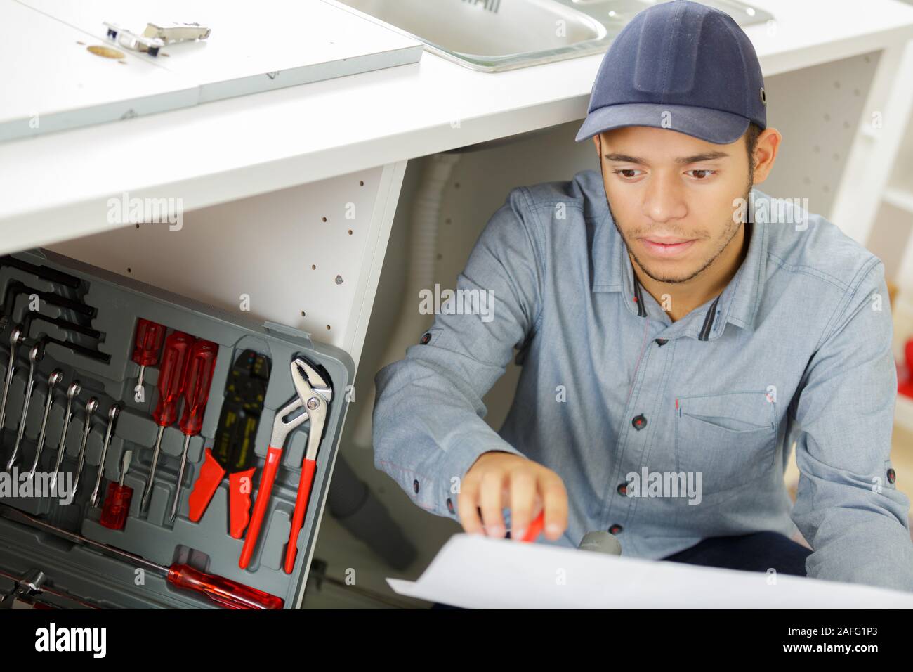 young man repair something inside kitchen cabinet under the sink Stock ...