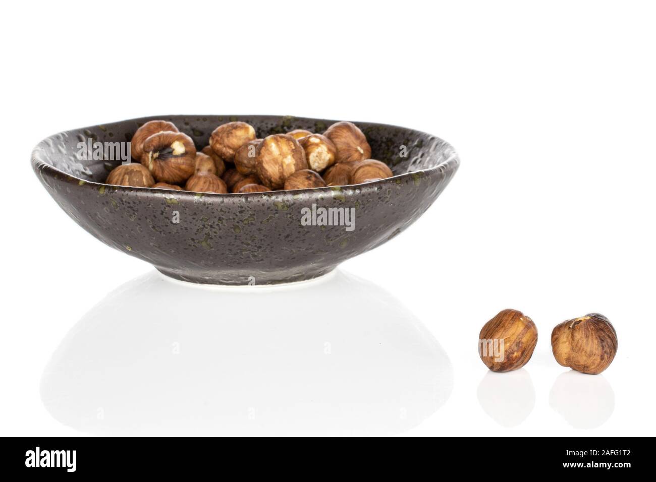 Lot of whole tasty brown hazelnut in glazed bowl isolated on white ...