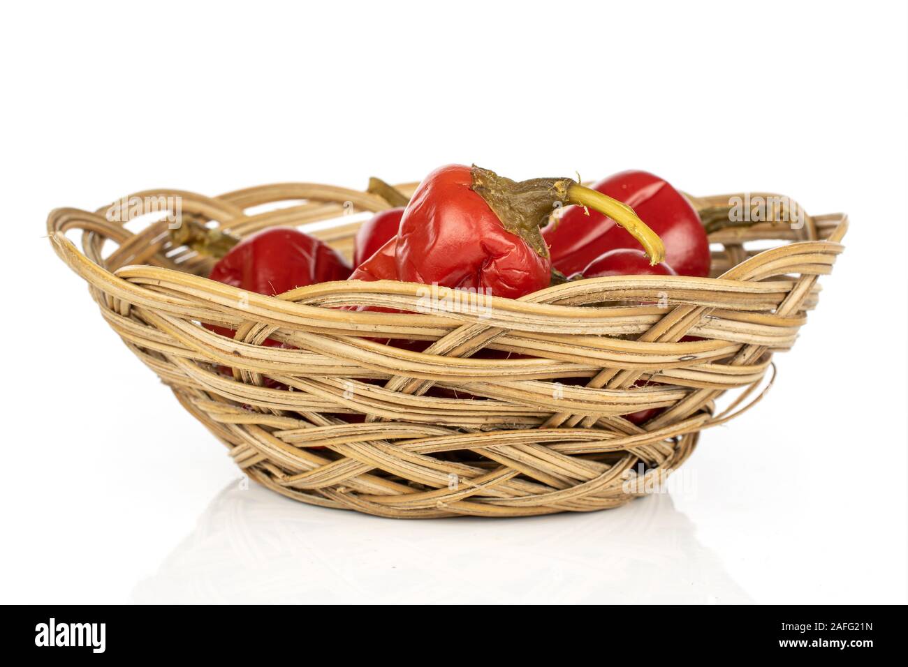 Lot of whole pickled red pepper in round rattan bowl isolated on white ...