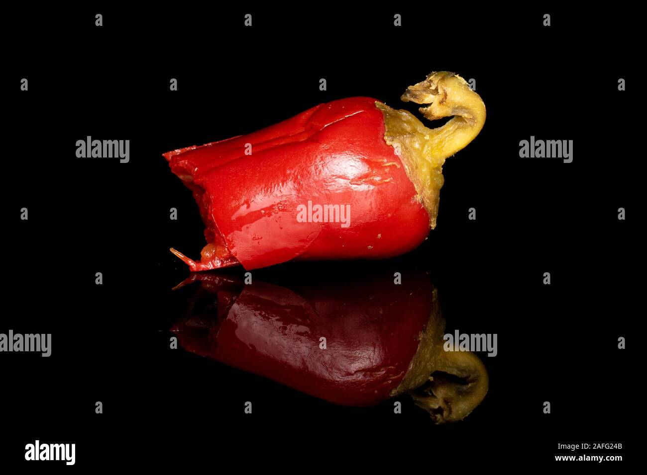 One half of bite pickled red pepper isolated on black glass Stock Photo ...