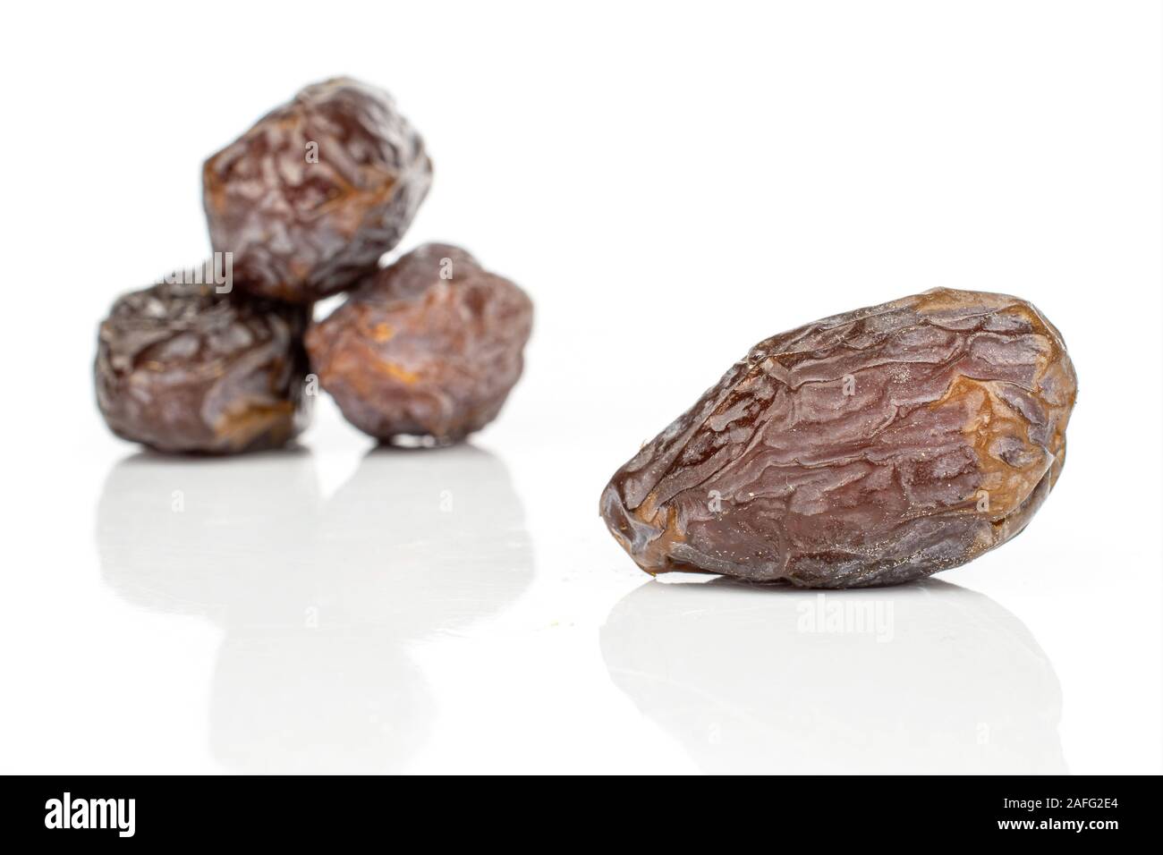 Group of four whole dried brown date fruit one in front isolated on ...