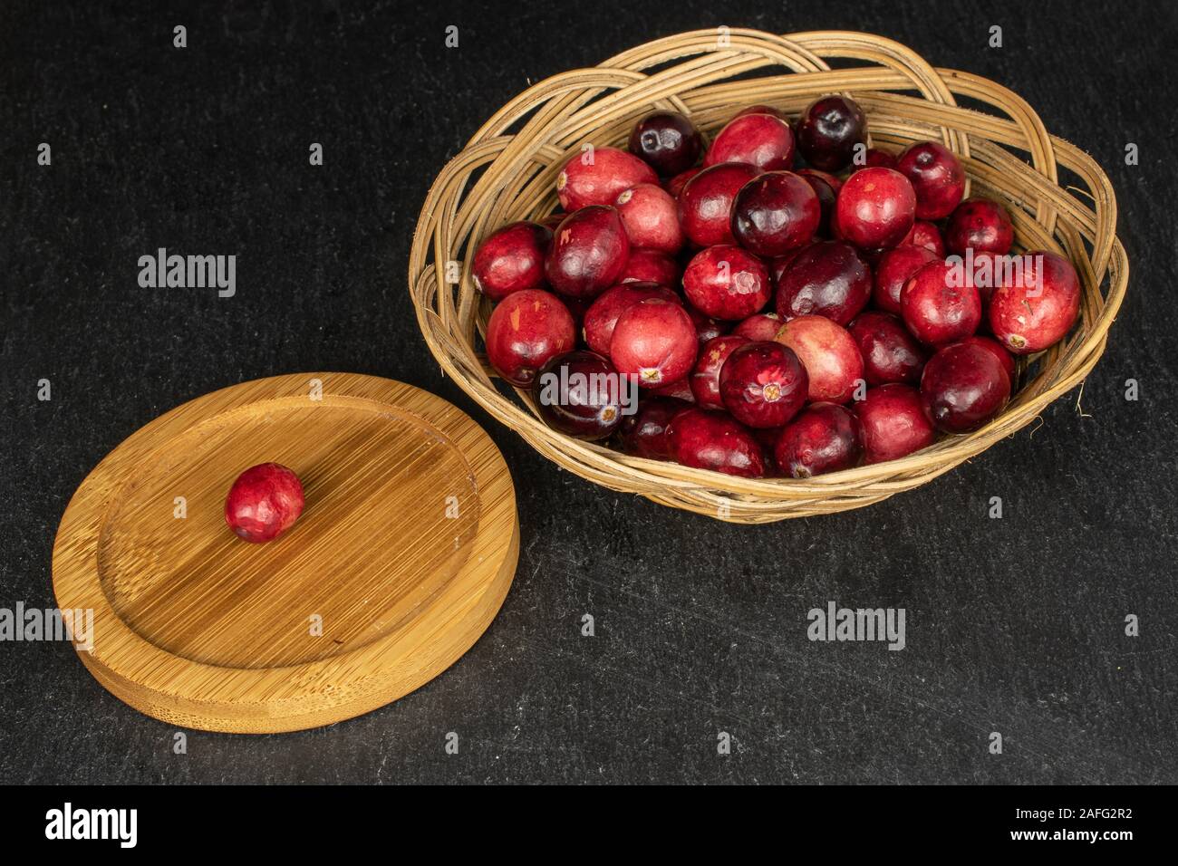 Lot of whole fresh red cranberry on round bamboo coaster in round ...