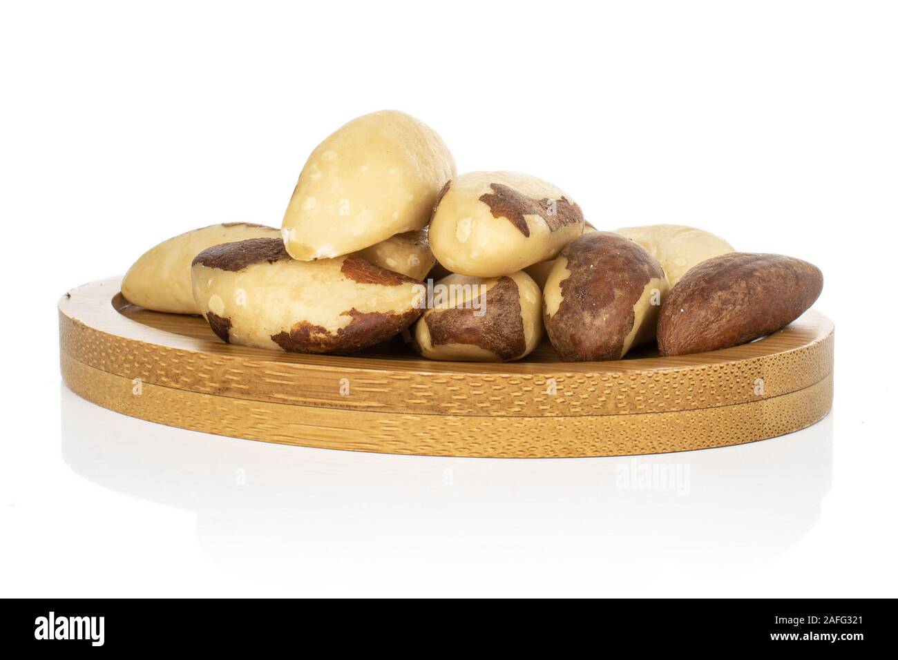 Lot of whole brazil brown nut on round bamboo coaster isolated on white ...