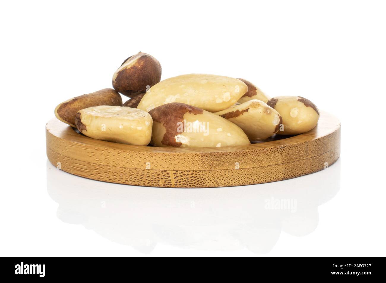 Lot of whole hulled brazil brown nut on round bamboo coaster isolated ...