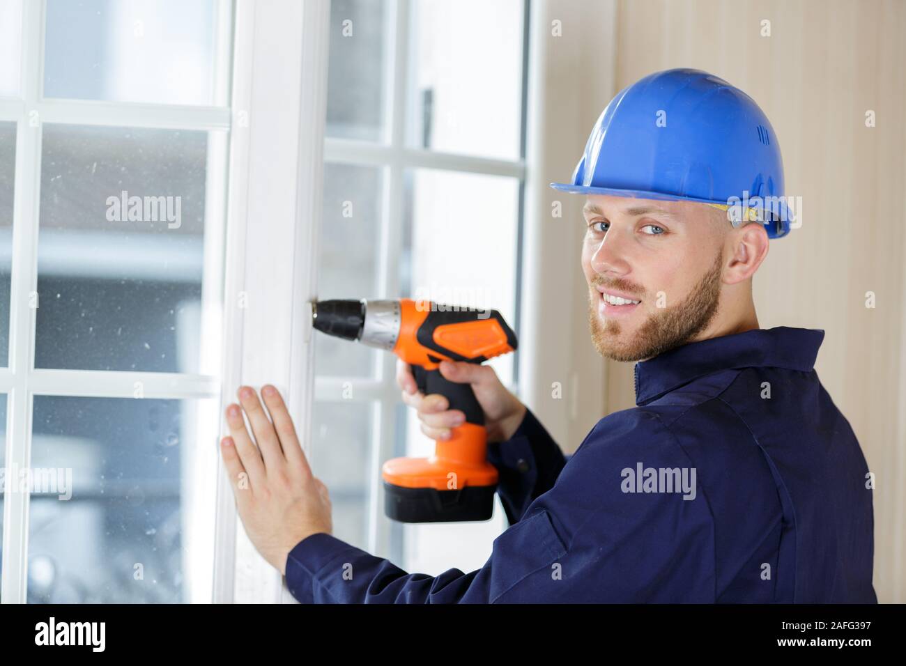 man drilling a hole in a window frame Stock Photo - Alamy