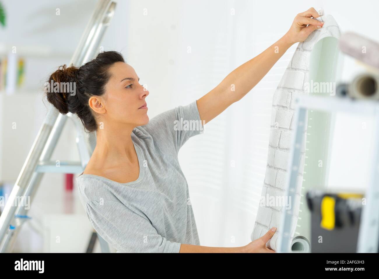 portrait of woman putting up wallpaper Stock Photo - Alamy