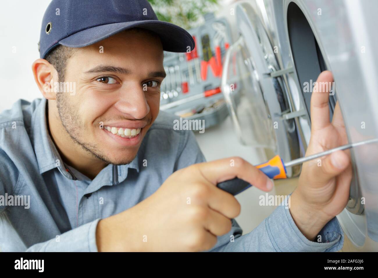 young serviceman using screwdriver to repair washing machine Stock ...