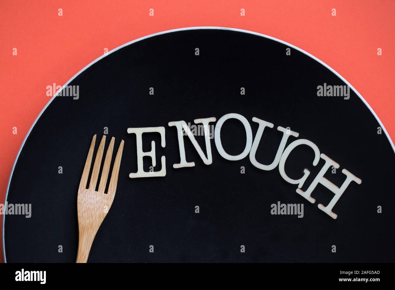A plate with a bamboo fork and the word "enough" in wooden letters ...