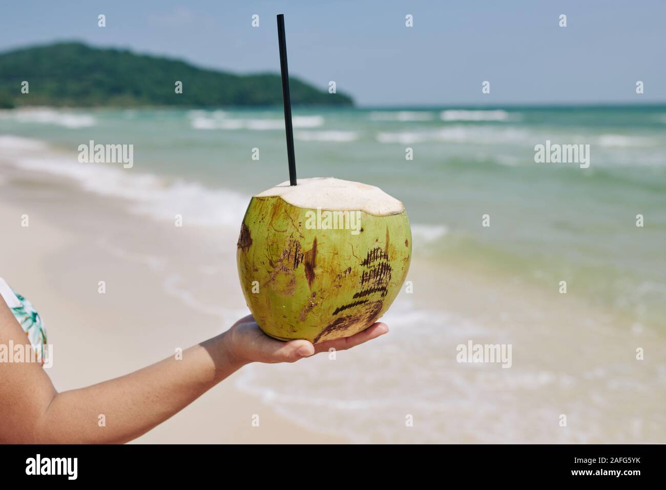 Hand holding coconut on beach hi-res stock photography and images - Alamy