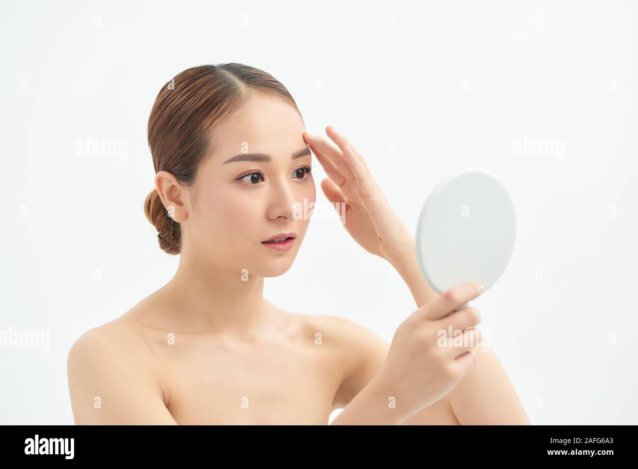 Young Asian woman with problem face looking at the mirror over white ...