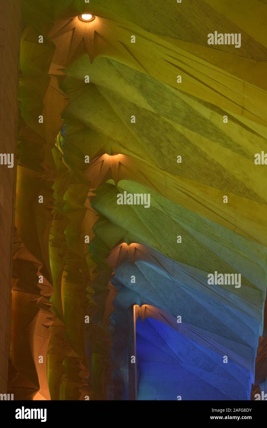 Colored bands of light stream through the high stained glass that line ...