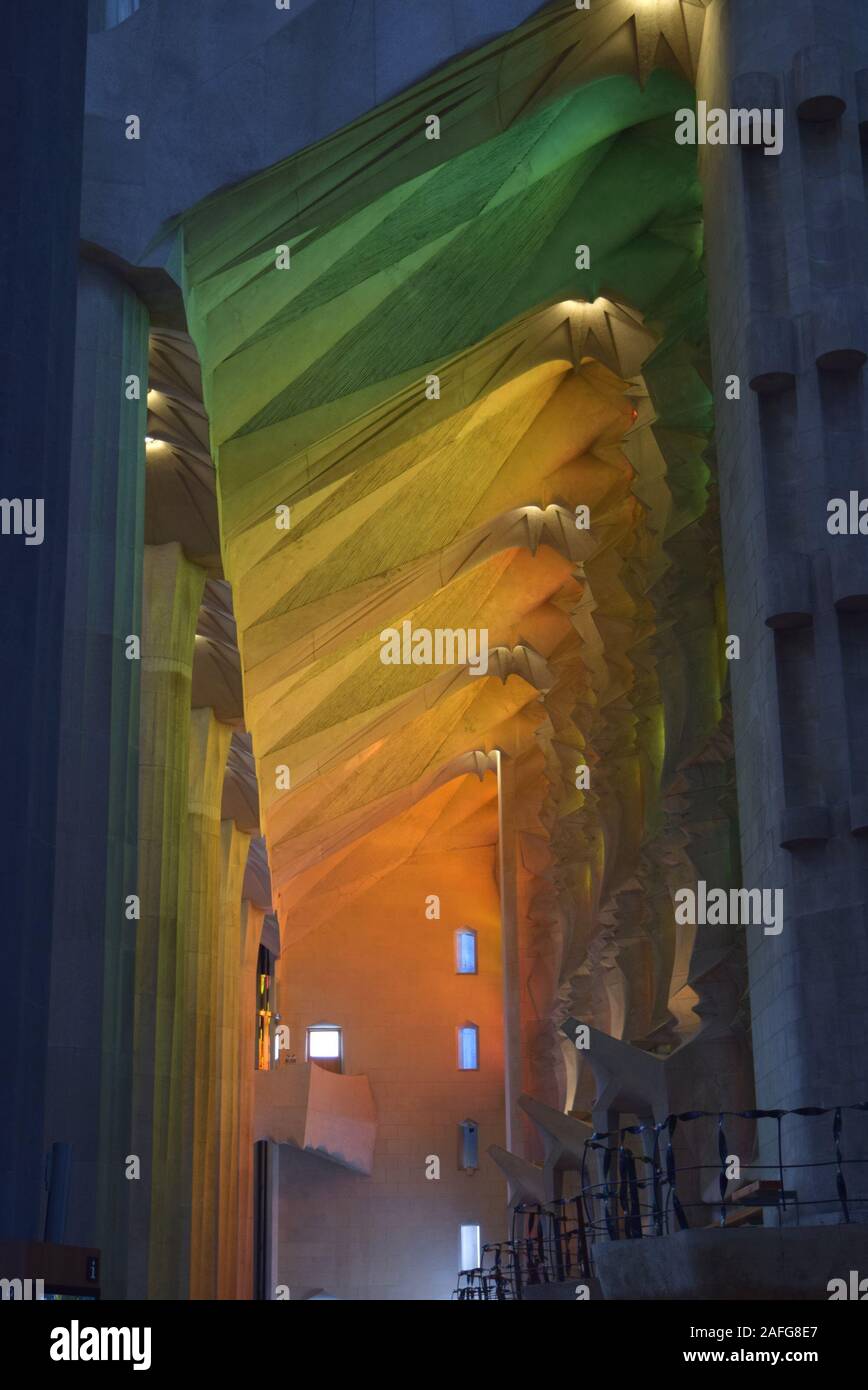 Colored bands of light stream through the high stained glass that line ...