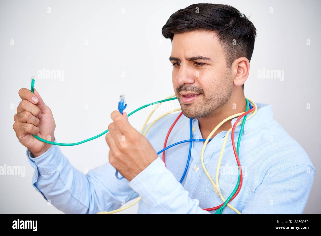 Portrait of confused young man looking at patch cords of different ...