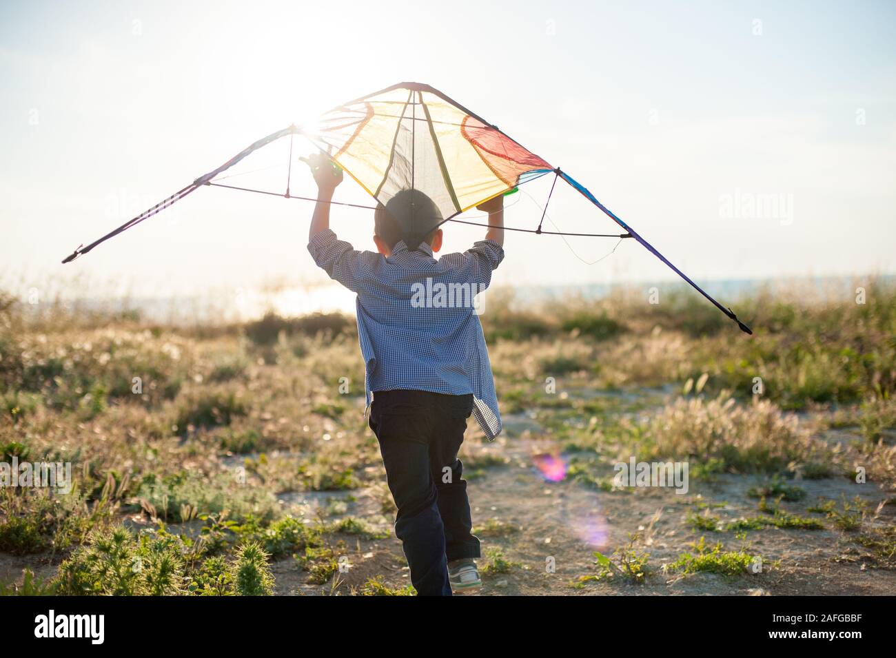 free active kid with kite in hands running towards sea horizon during ...