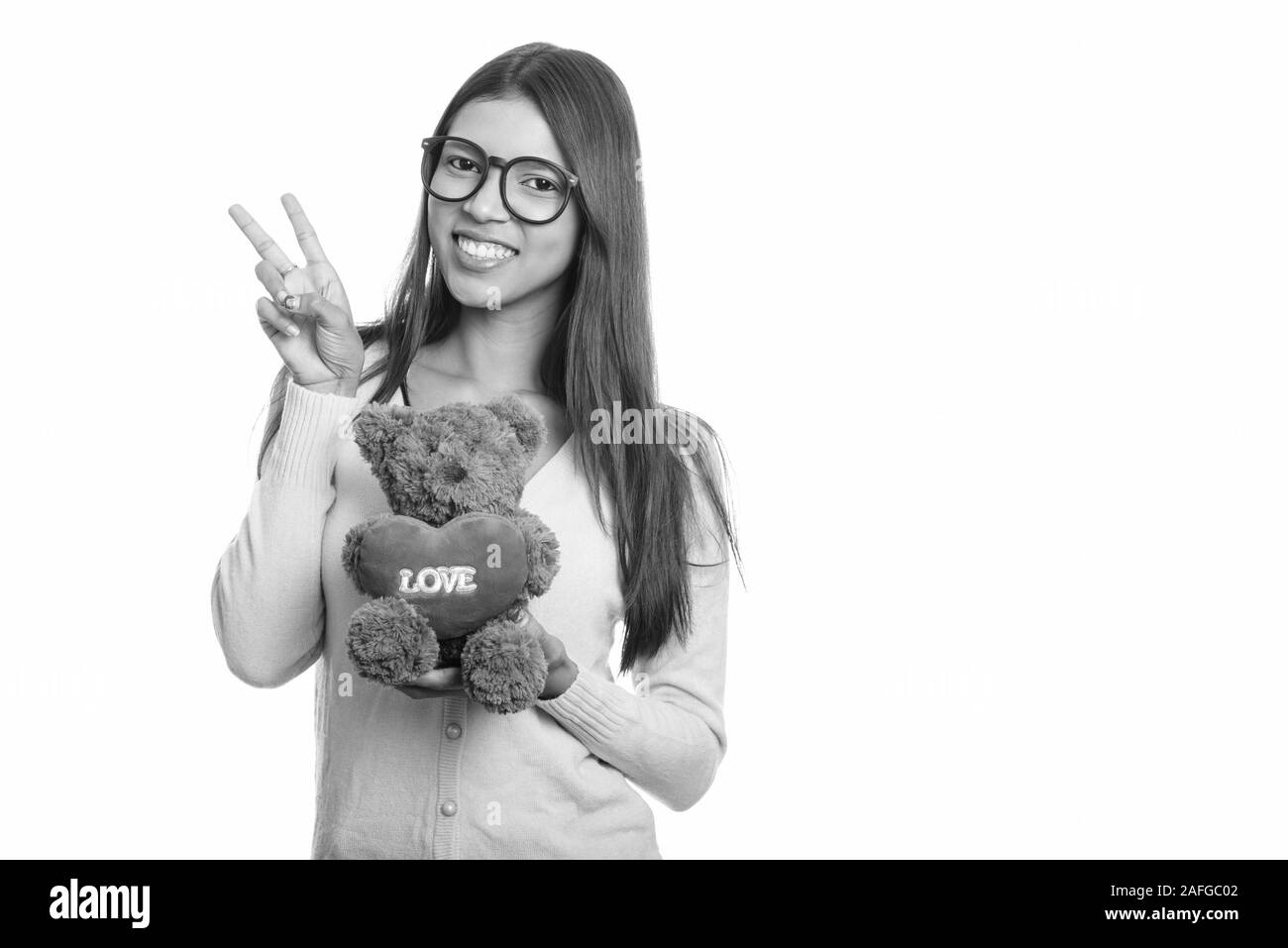 Young happy Brazilian nerd woman giving peace sign while holding teddy ...