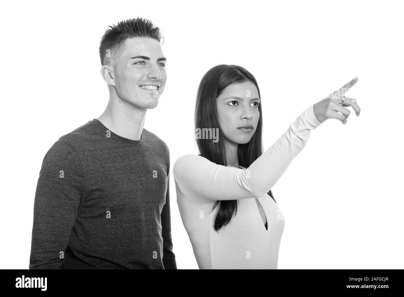 Studio shot of young couple with woman pointing finger and happy man ...