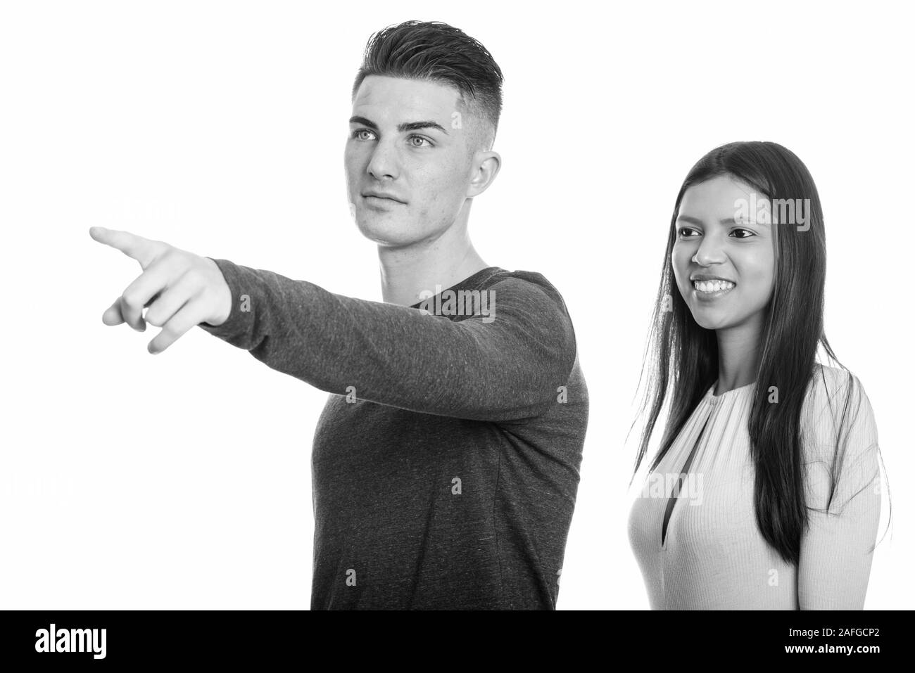 Studio shot of young couple with man pointing finger and happy woman ...
