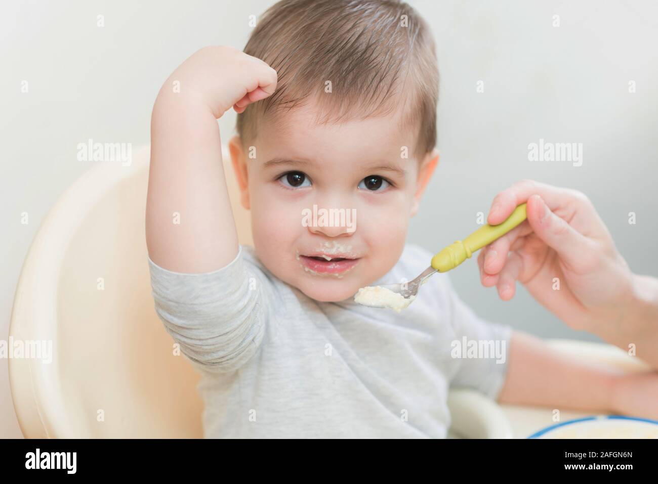 mom in the kitchen is feeding the baby porridge Stock Photo - Alamy