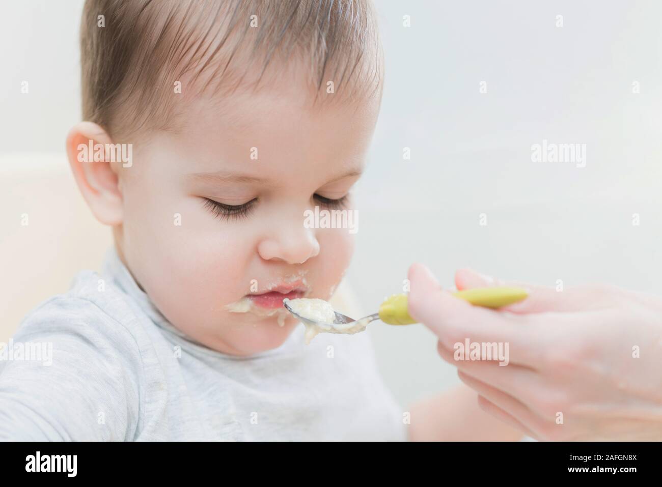mom in the kitchen is feeding the baby porridge Stock Photo - Alamy