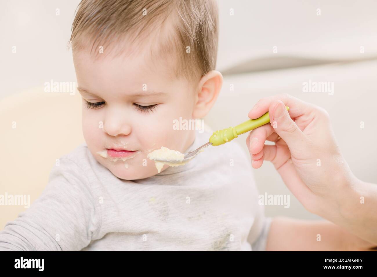 mom in the kitchen is feeding the baby porridge Stock Photo - Alamy