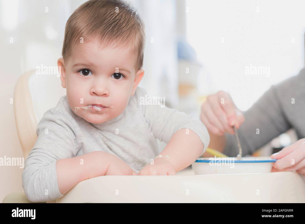 mom in the kitchen is feeding the baby porridge Stock Photo - Alamy