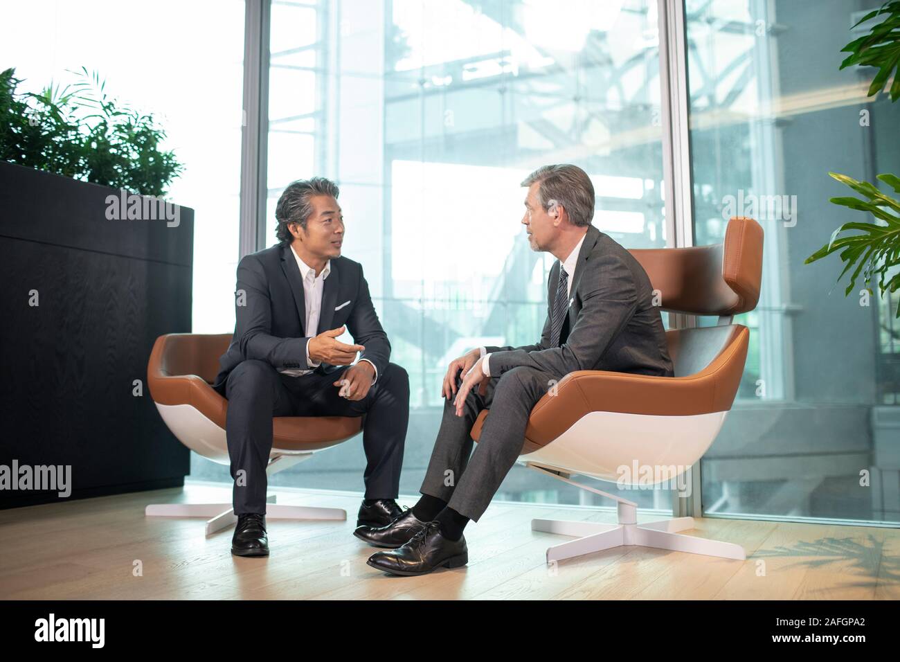 Two businessmen talking in office Stock Photo - Alamy