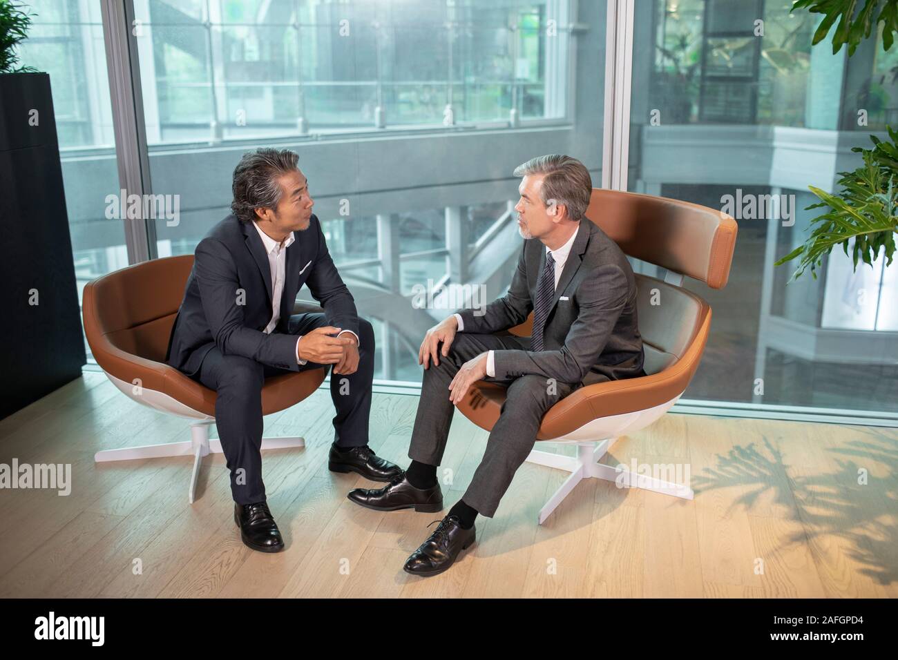 Two businessmen talking in office Stock Photo - Alamy