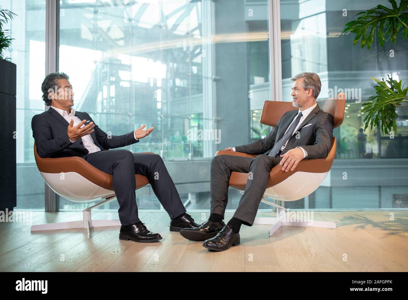 Two businessmen talking in office Stock Photo - Alamy