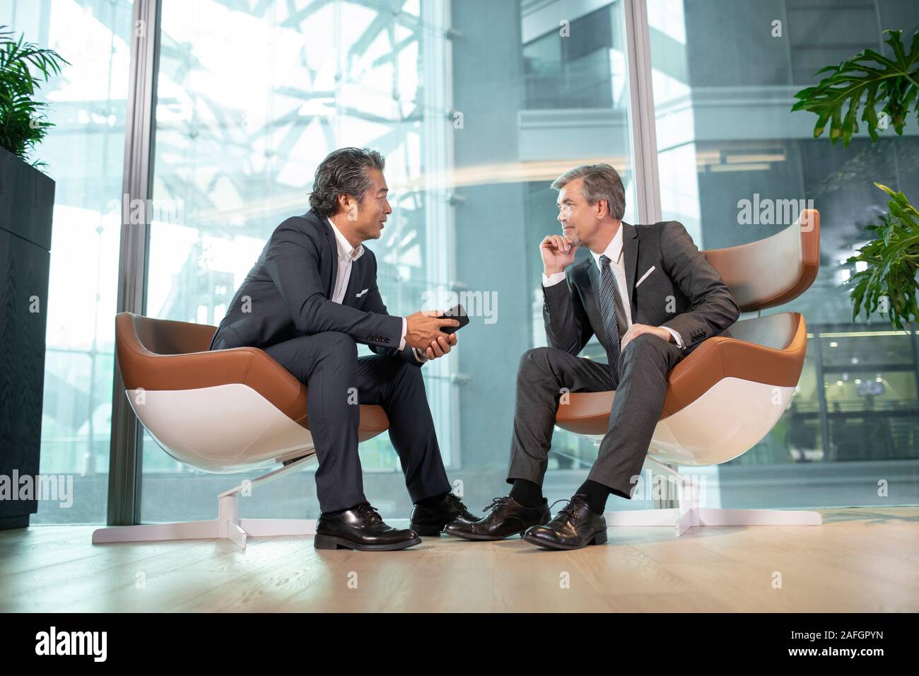Two businessmen talking in office Stock Photo - Alamy