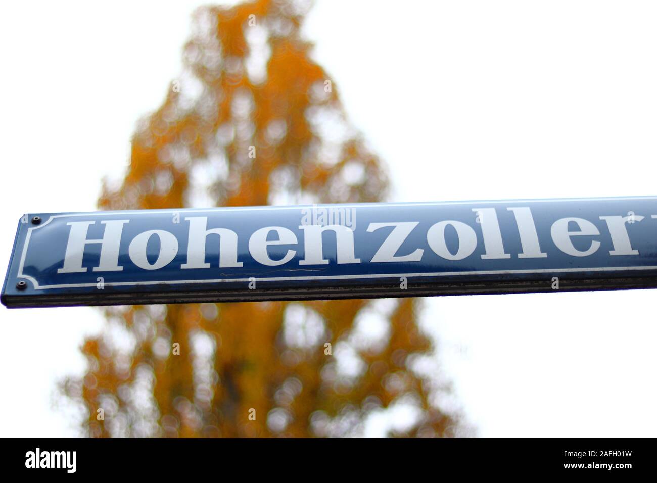 Closeup of a sign of a street name with yellow trees on a blurry ...