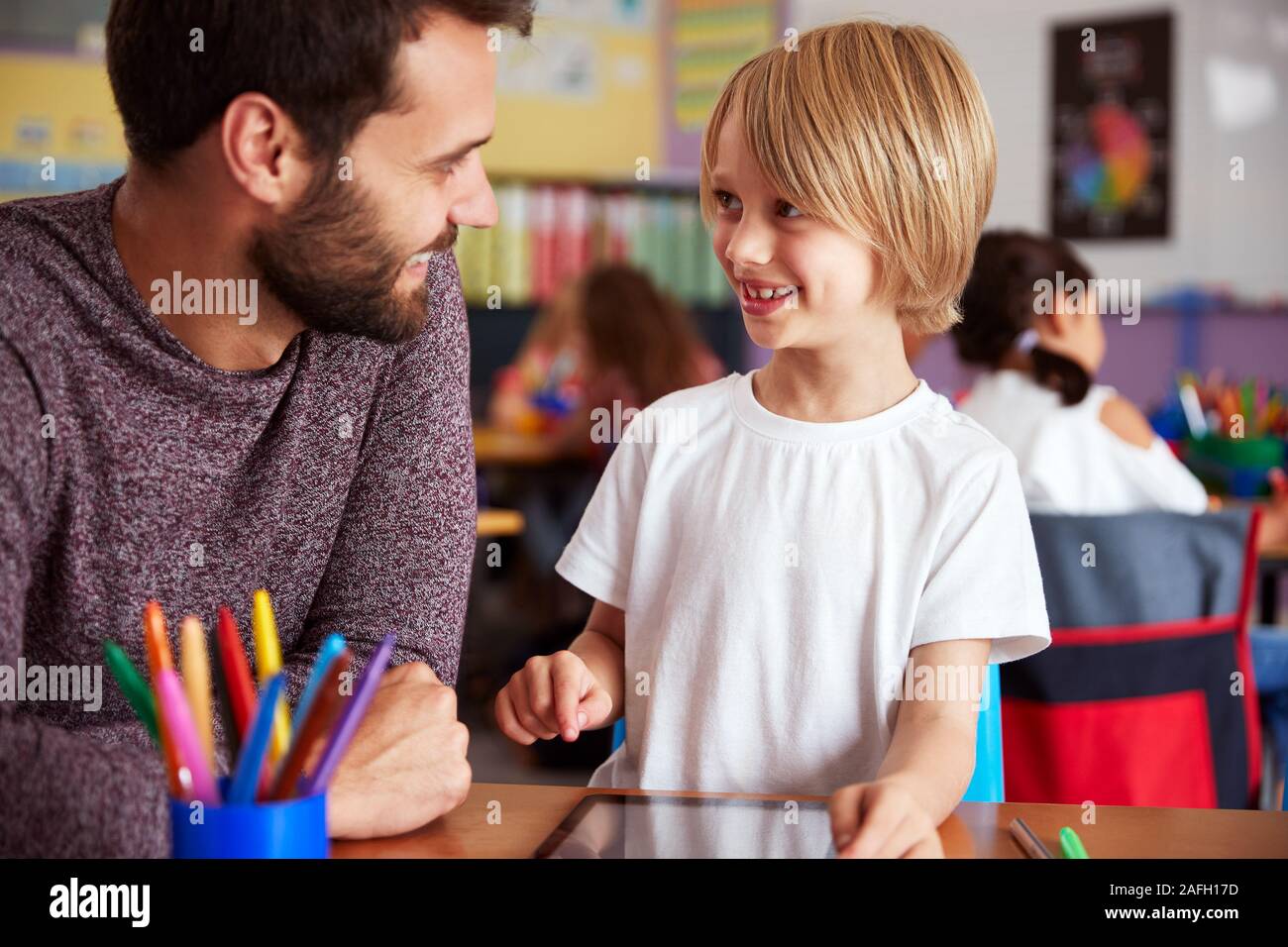 Elementary School Teacher And Male Pupil Drawing Using Digital Tablet ...