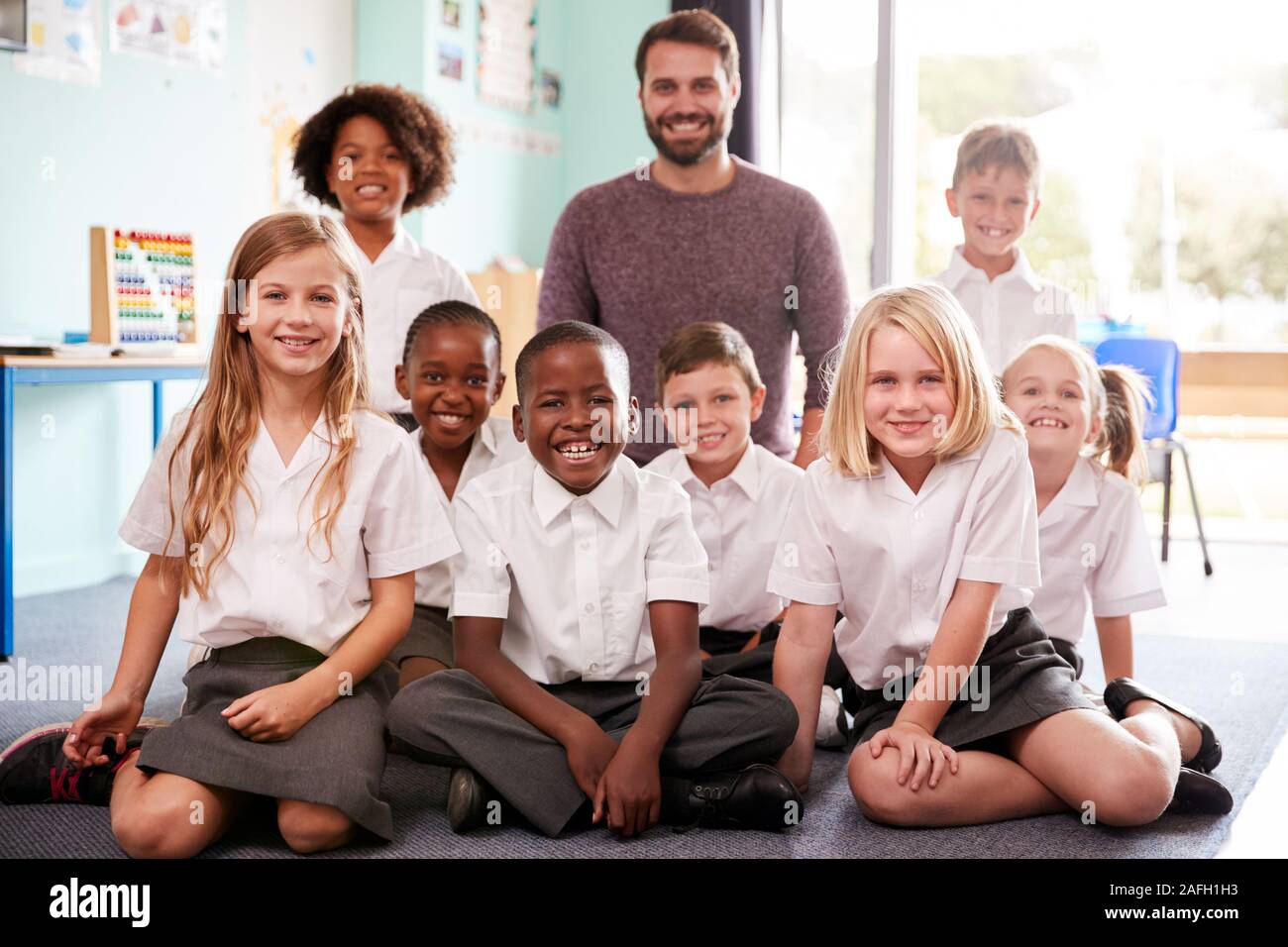 Portrait Of Elementary School Pupils Wearing Uniform Sitting On Floor ...