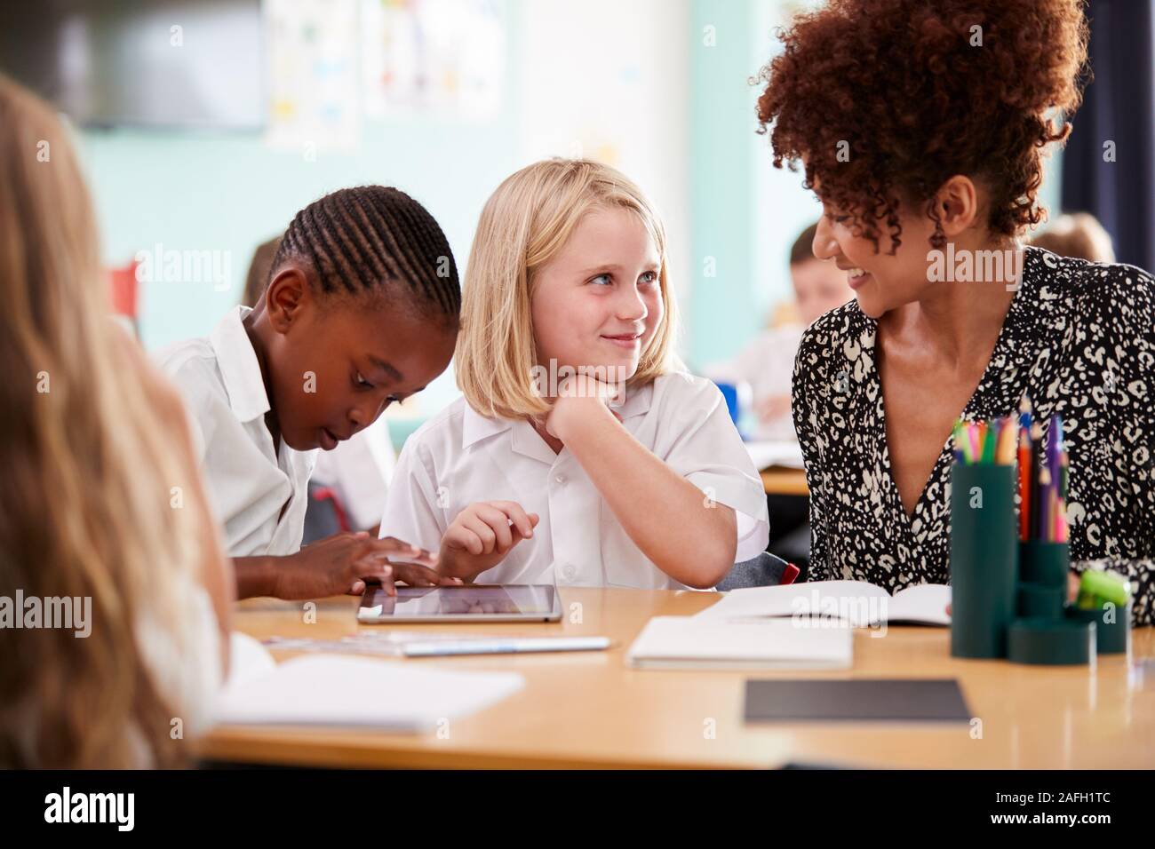 Female Teacher With Two Elementary School Pupils Wearing Uniform Using ... Female Teacher With Two Elementary School Pupils Wearing Uniform Using ...