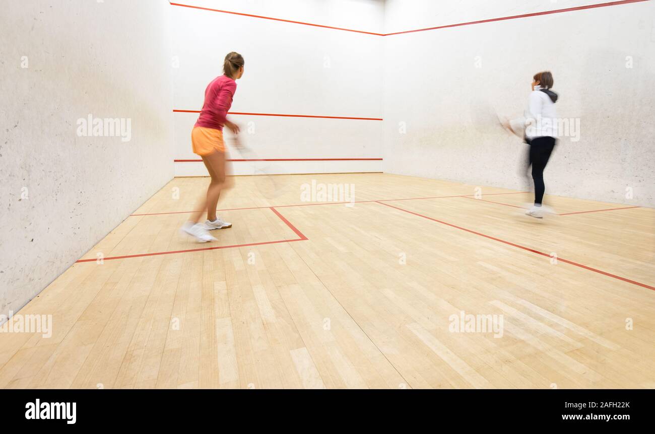 Two female squash players in action on a squash court (motion blurred ...
