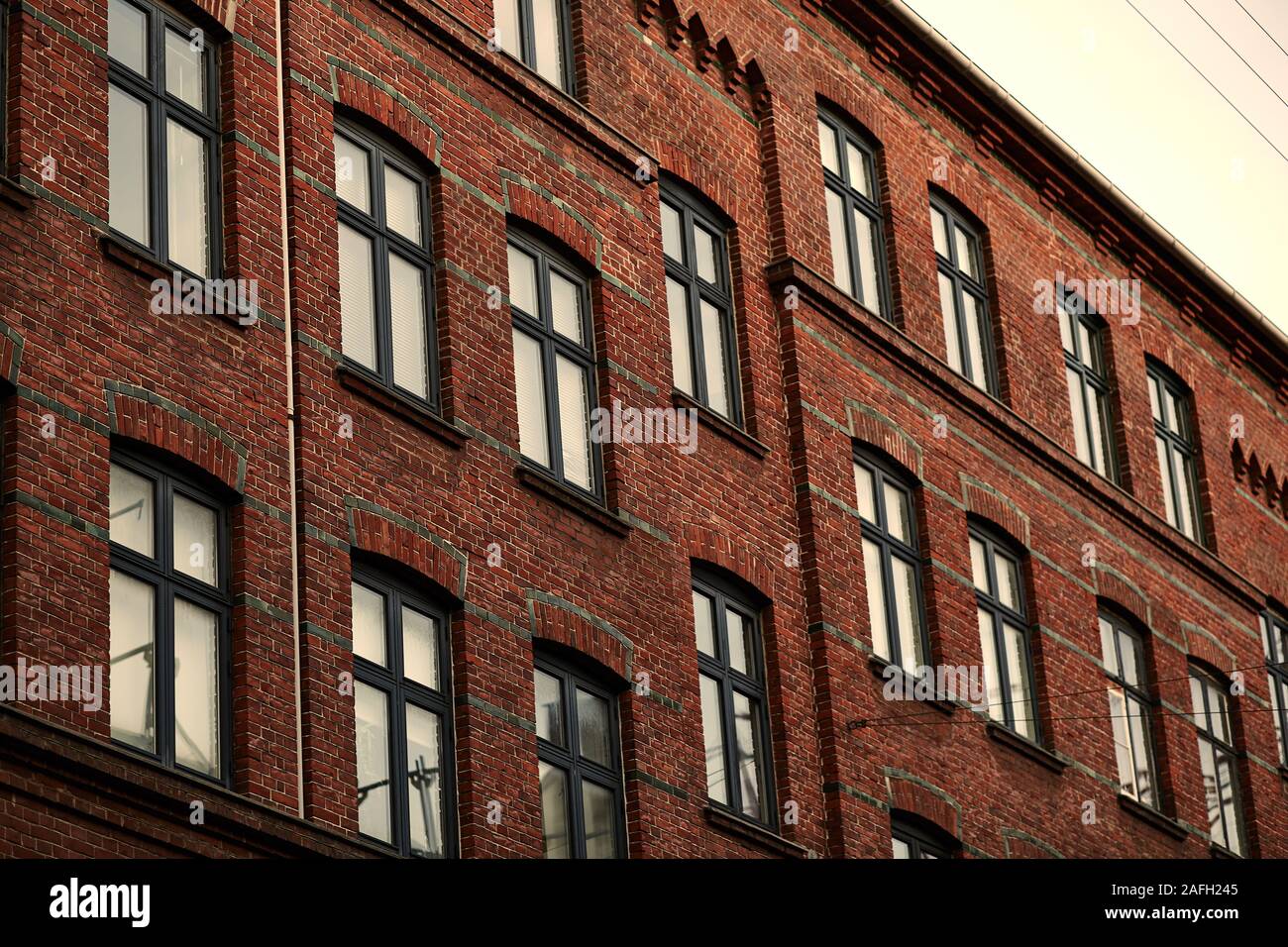 Modern red stone building with large black windows under a grey sky ...