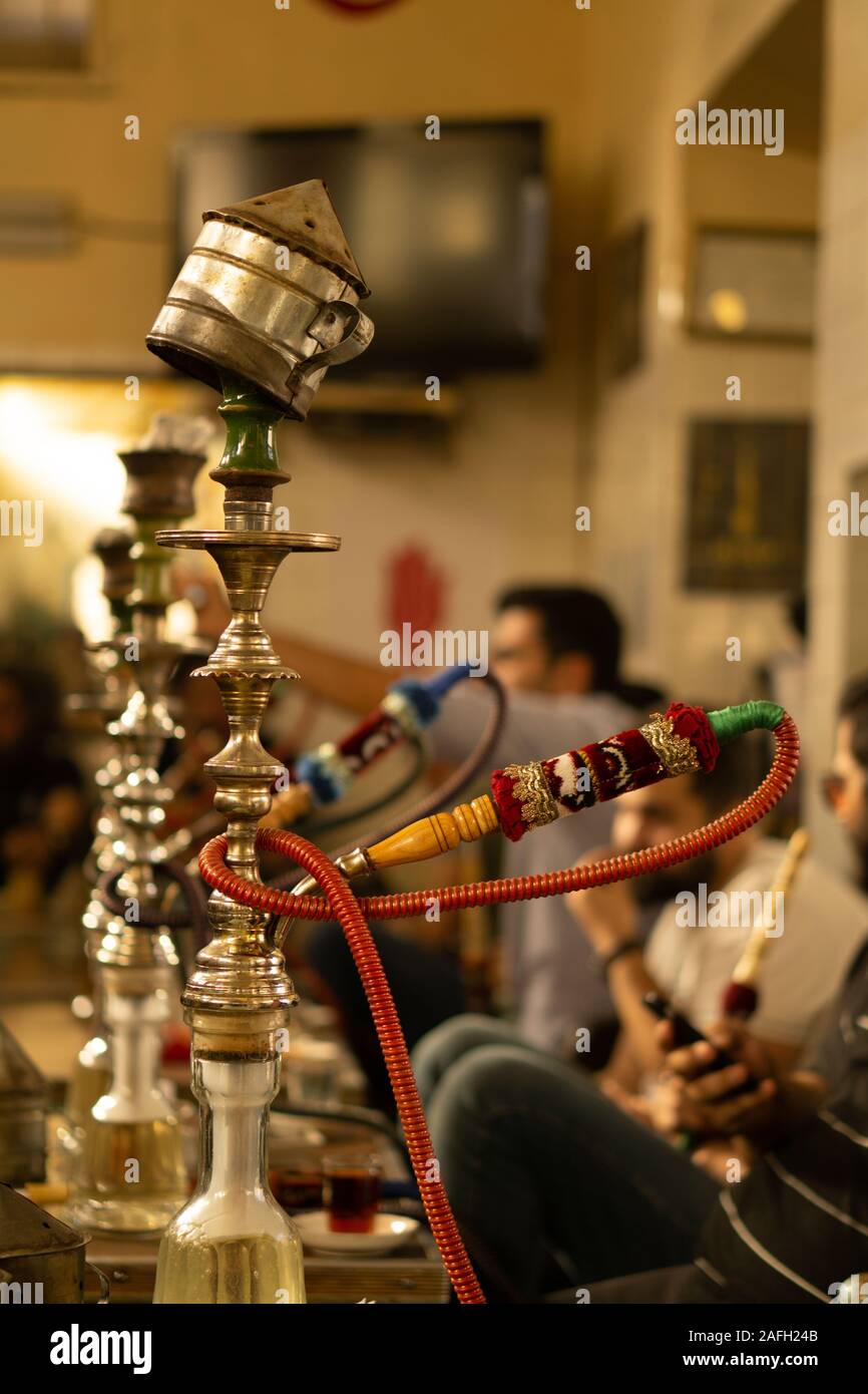 Closeup of a colorful hookah on a table with people sitting in a house ...