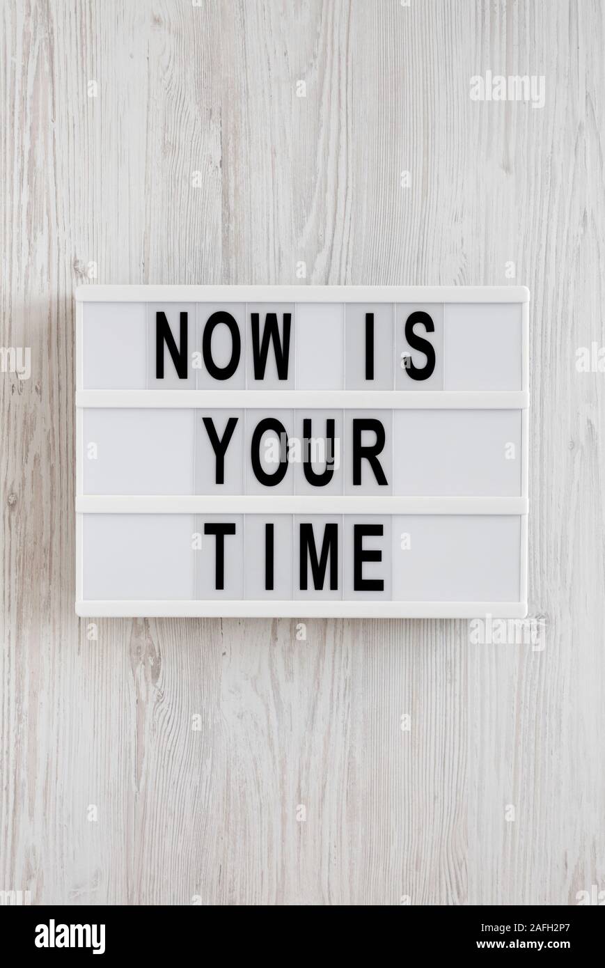 'Now is your time' words on a modern board on a white wooden background ...