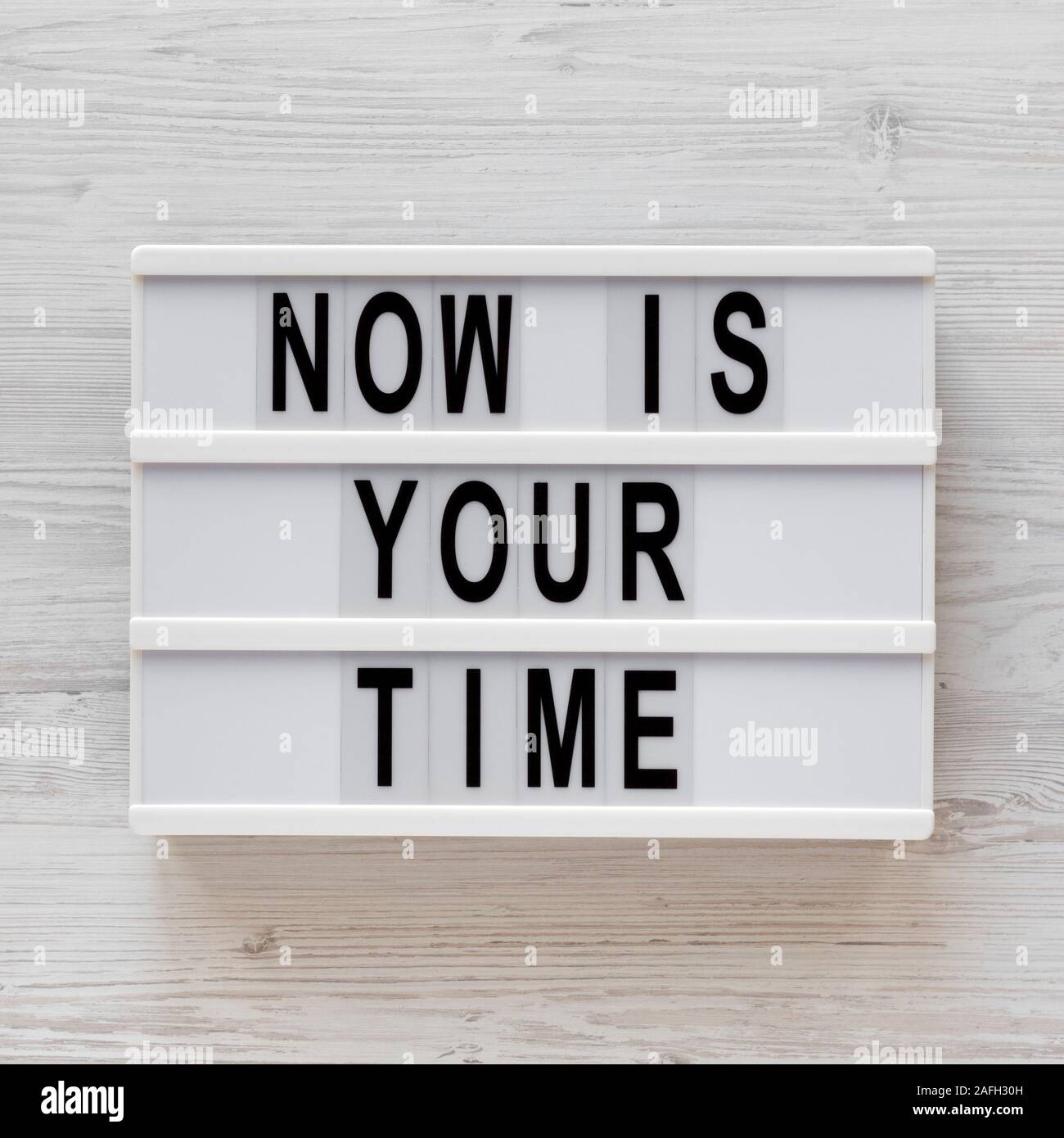 'Now is your time' words on a modern board on a white wooden background ...