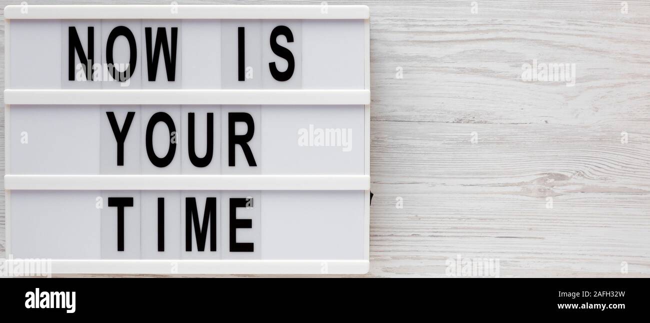'Now is your time' words on a modern board on a white wooden background ...
