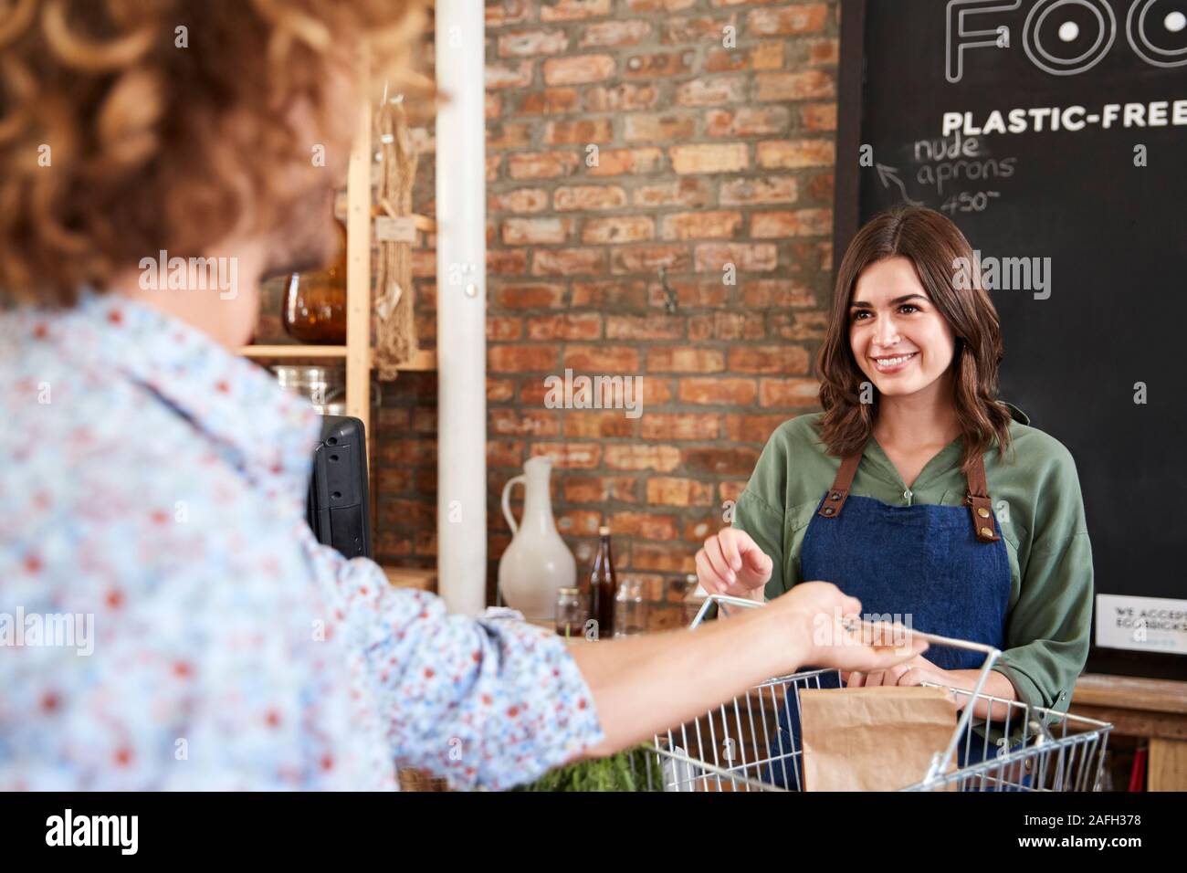 Customer Paying For Shopping At Checkout Of Sustainable Plastic Free ...