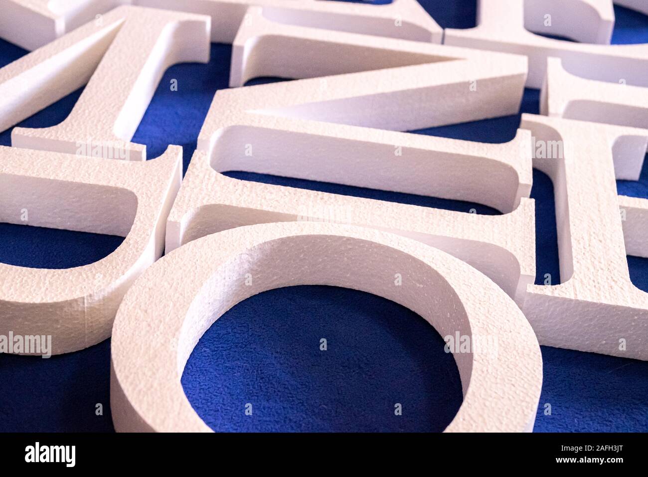 white letters cut out of foam without painting on a blue background ...