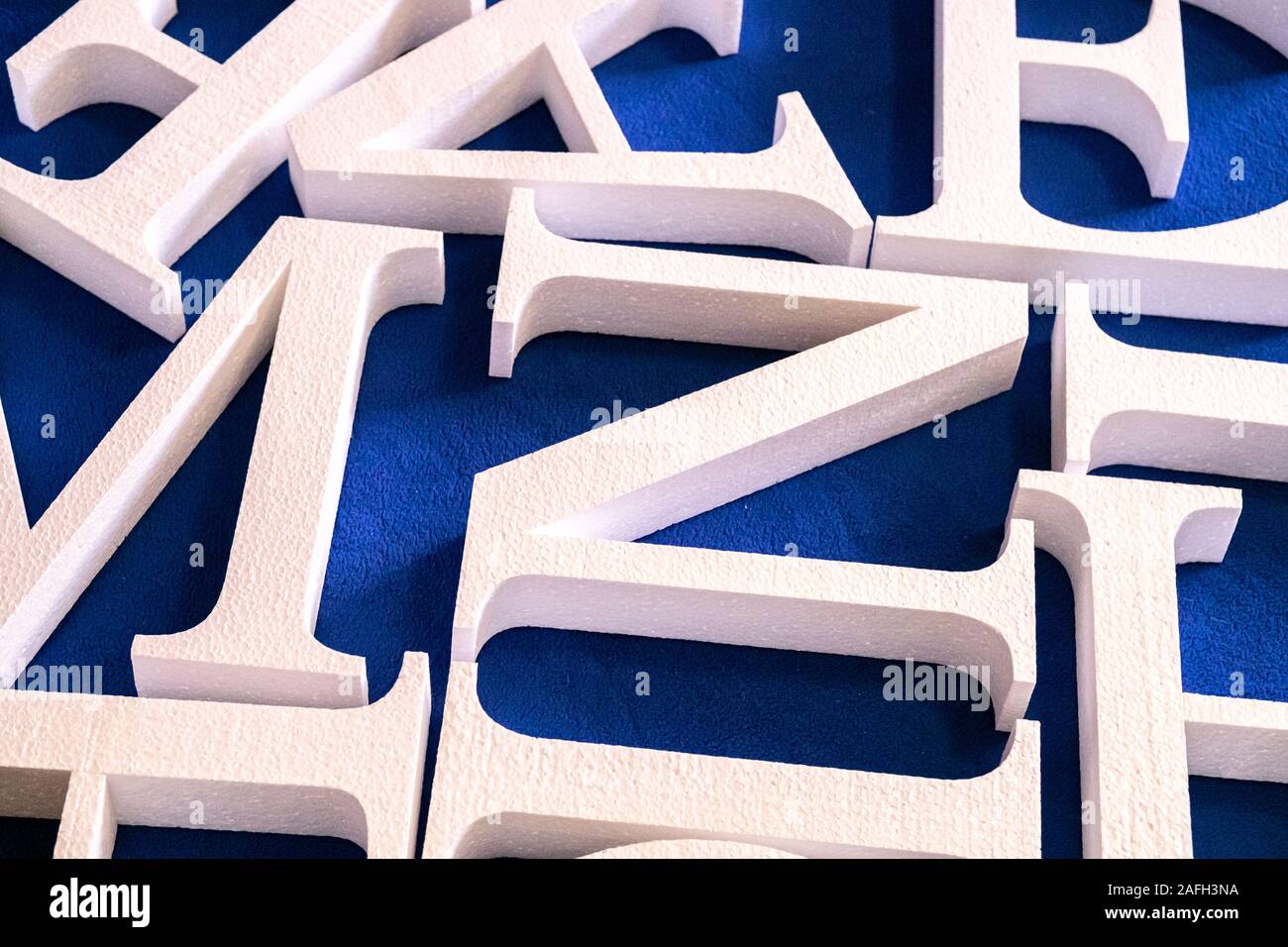 white letters cut out of foam without painting on a blue background ...