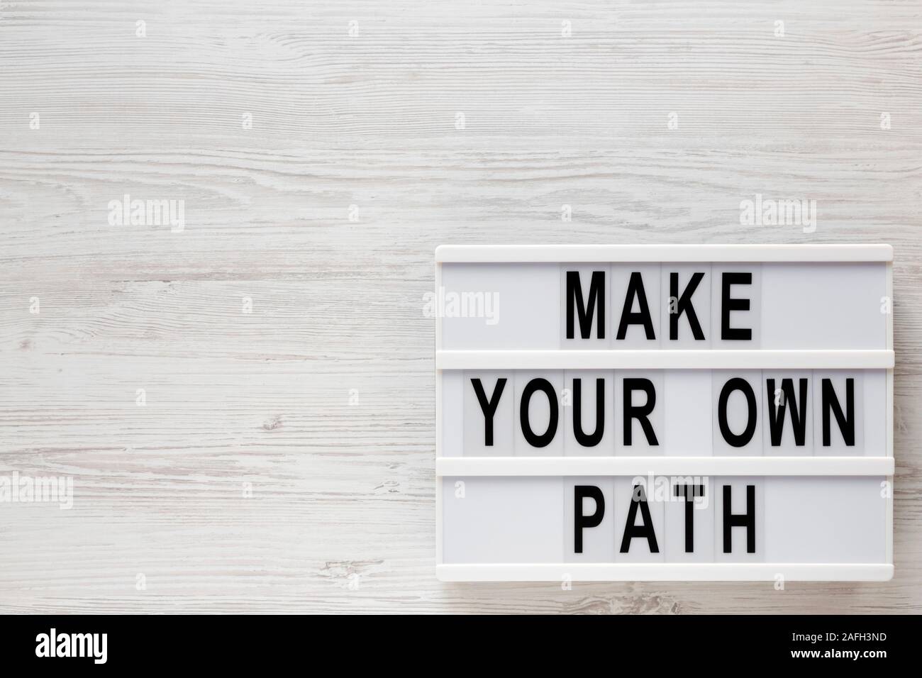 'Make your own path' words on a modern board on a white wooden ...