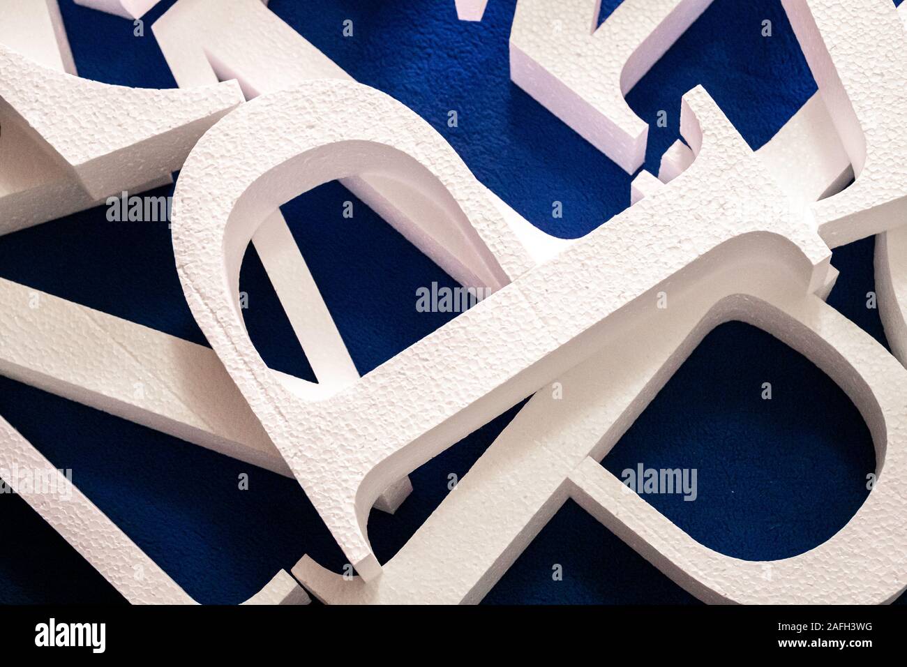 white letters cut out of foam without painting on a blue background ...