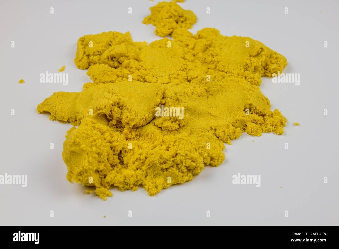 yellow kinetic sand scattered on a white table Stock Photo - Alamy